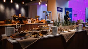 Uma mesa de buffet com diversos alimentos e uma máquina de café.