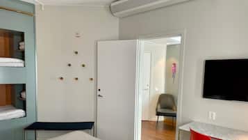 Quarto de hotel com duas camas, uma escrivaninha, uma cadeira, uma televisão e um guarda-roupa.