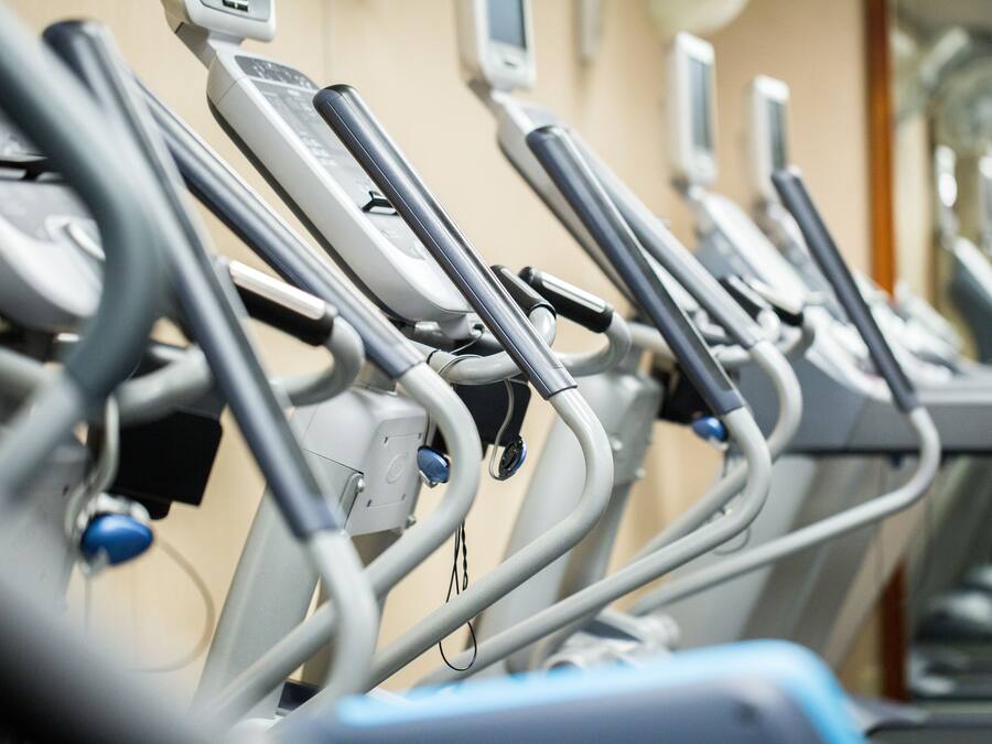 Uma fileira de bicicletas ergométricas paradas em uma academia.
