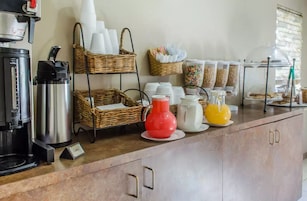 Uma mesa de pequeno-almoço com máquinas de café, cestas e dispensadores.