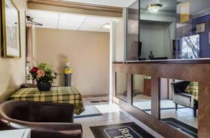 Um saguão de hotel com uma mesa xadrez, uma planta em vaso e um balcão de recepção.