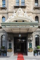 Entrada do Hotel Windsor, com tapete vermelho, decorações elaboradas e uma placa sobre a porta.