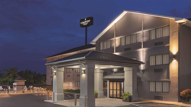 Um hotel moderno com entrada coberta, vários andares e uma placa indicando ser um Country Inn & Suites.