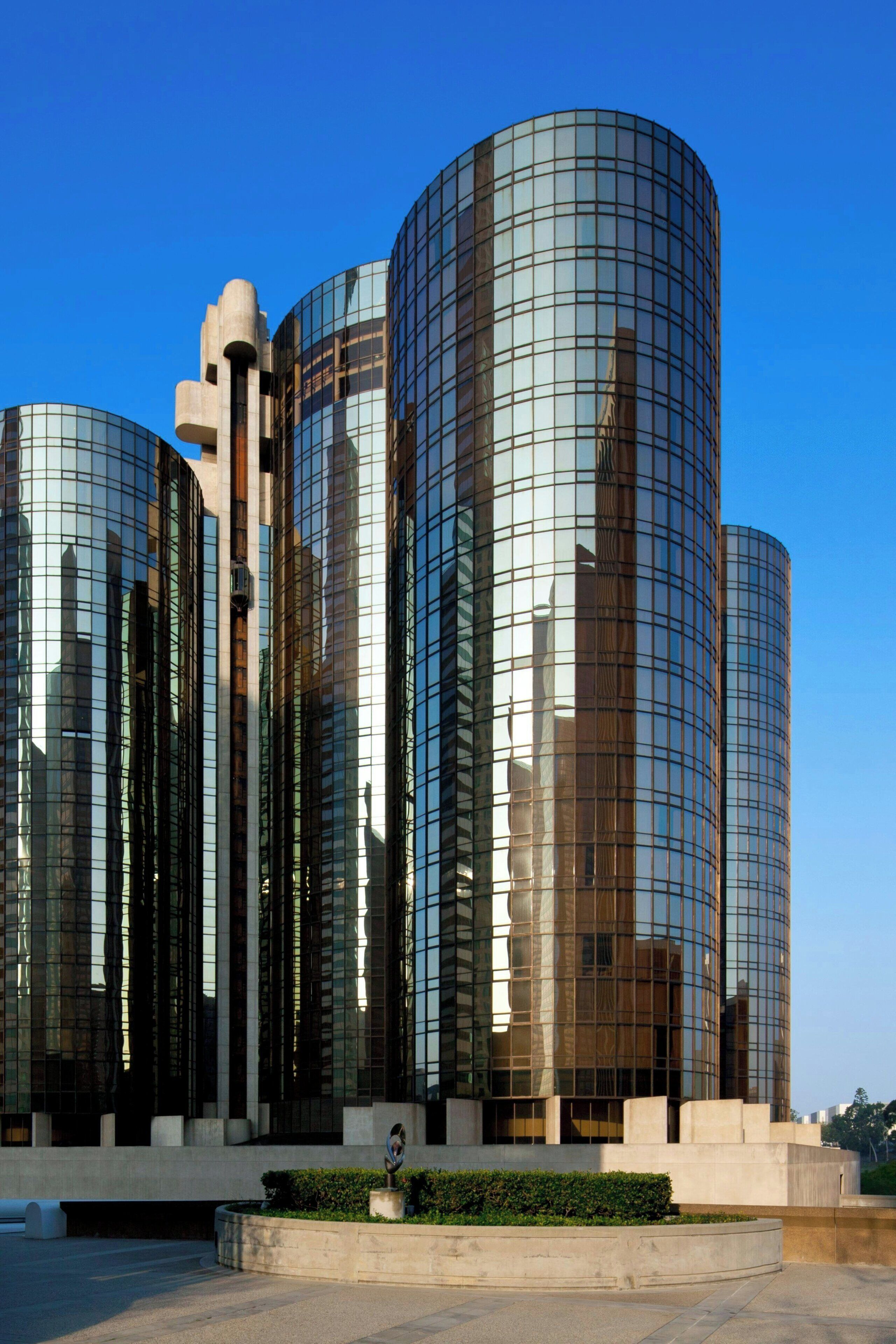 Um edifício moderno com fachadas de vidro cilíndricas e uma estrutura central de concreto.