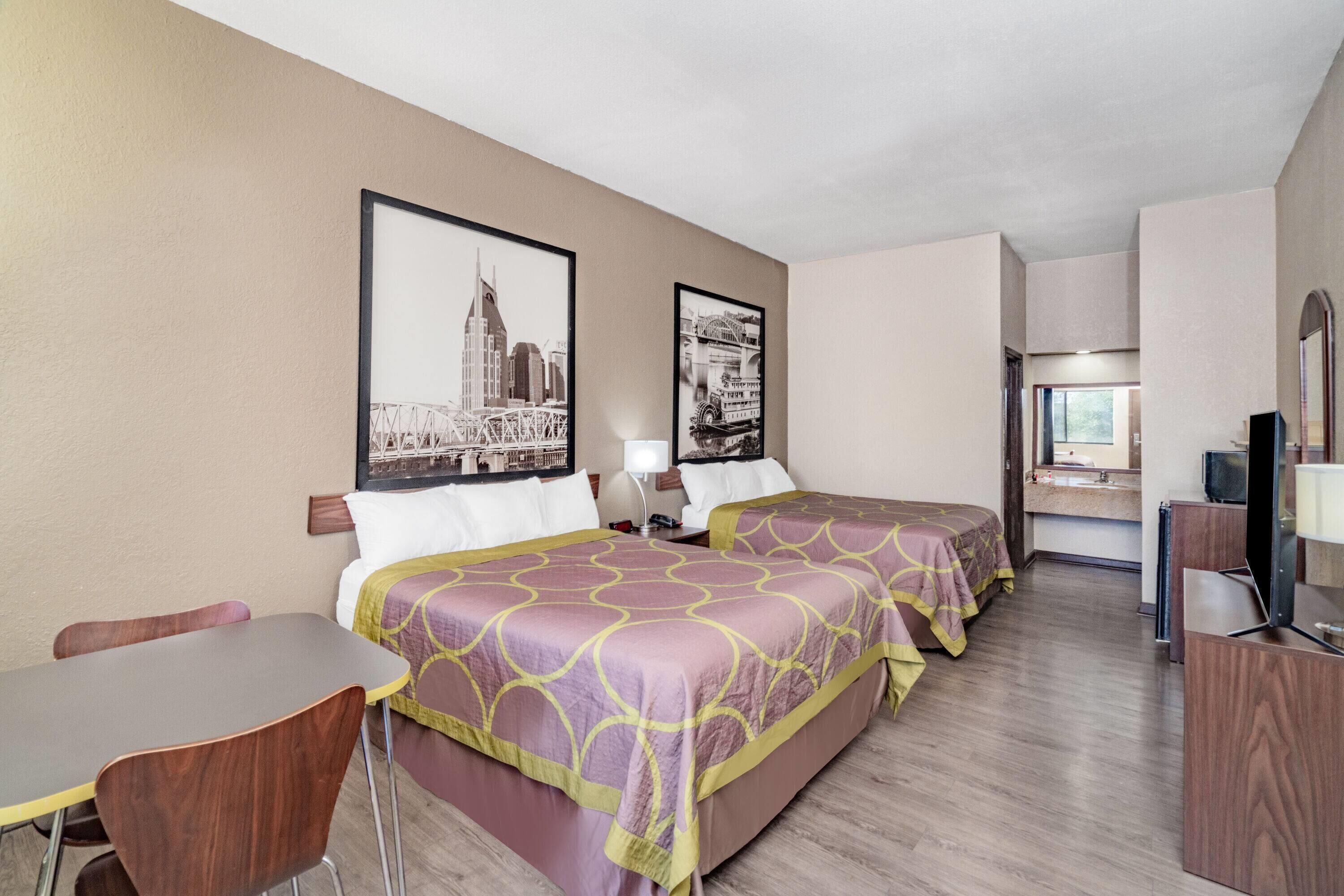 Quarto de hotel com duas camas, uma escrivaninha e uma televisão.