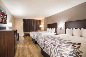 Quarto de hotel com cama grande, escrivaninha, televisão e cortina.