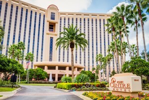 Um hotel com um edifício grande, palmeiras e uma placa indicando Rosen Centre Hotel.
