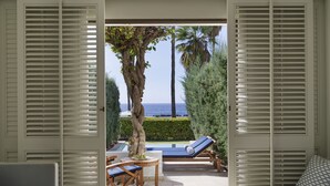 Quarto com vista para o mar, piscina e móveis de exterior.