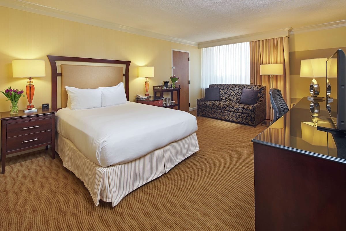 Quarto de hotel com uma cama grande, uma escrivaninha, uma cadeira e um sofá.