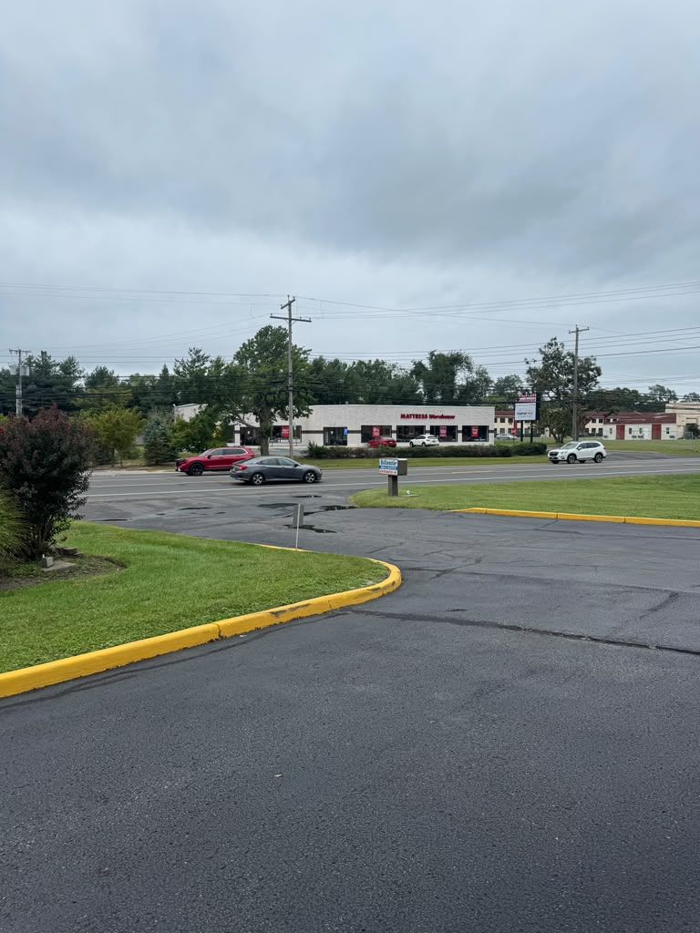 Um estacionamento com um edifício ao fundo identificado como 'Mattress Warehouse'.