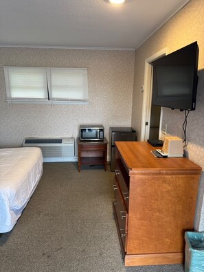 Quarto de hotel com cama, escrivaninha, televisão e aquecedor.