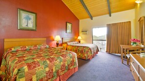 Quarto de hotel com duas camas, teto de madeira, varanda com vista e escrivaninha com abajur.