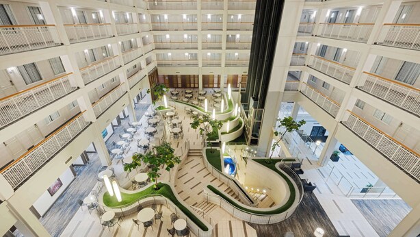 Um átrio de vários níveis com uma escadaria espiral central, várias áreas de estar e uma piscina.