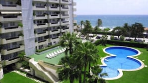 Um hotel com vários andares, piscina e vista para o oceano.