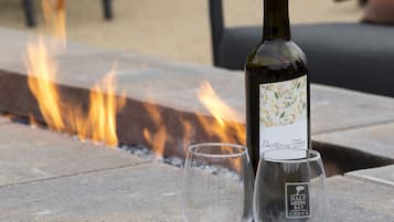 Uma garrafa de vinho e duas taças sobre uma superfície de pedra perto de uma lareira.