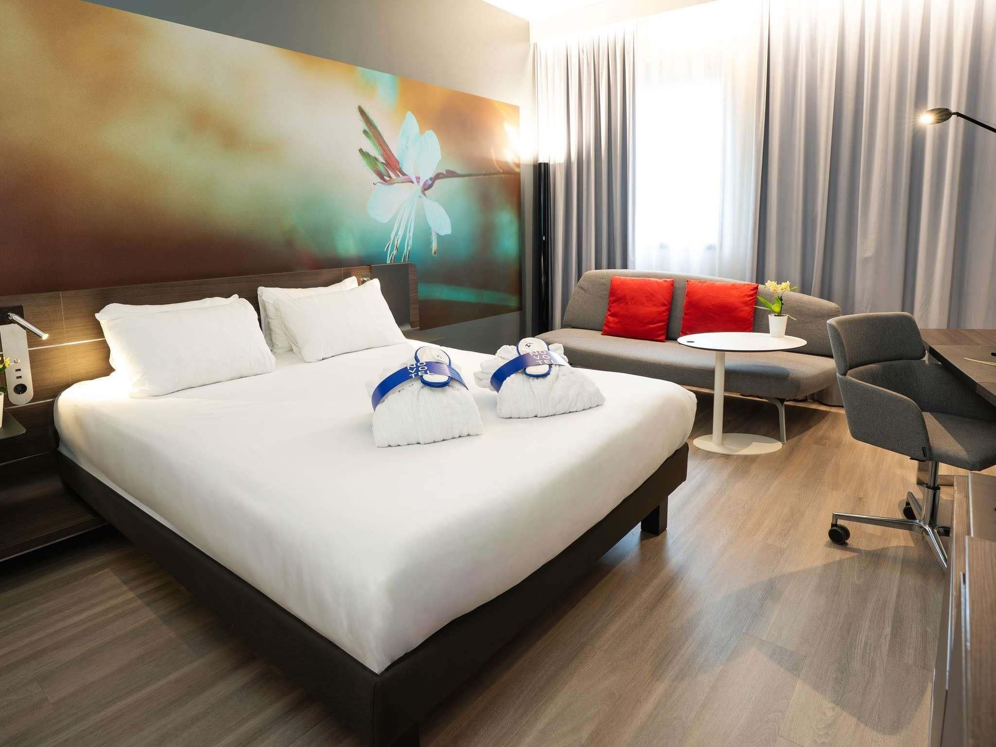 Quarto de hotel com uma cama grande, um sofá, uma mesa pequena e uma cadeira.