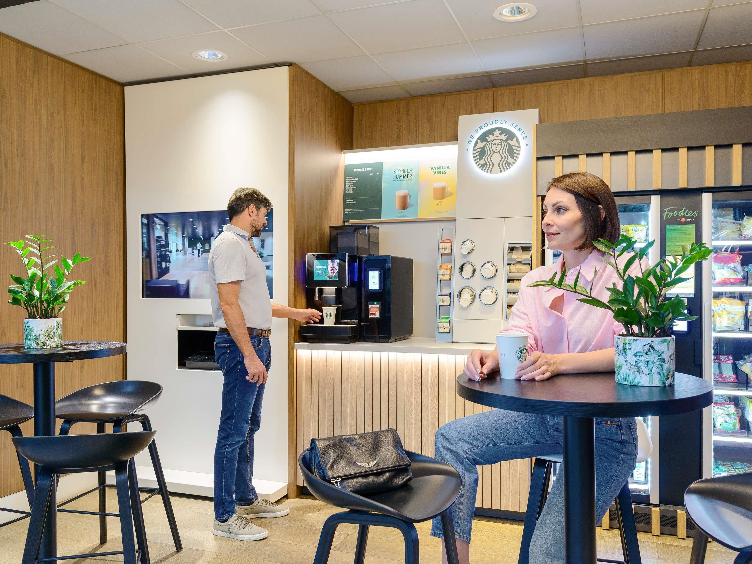 Interior de uma cafeteria Starbucks, com balcão, área de estar e vitrine refrigerada.