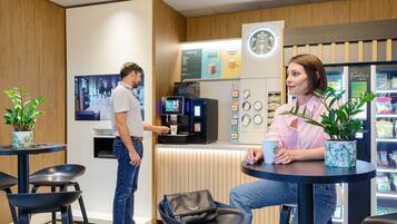 Interior de uma cafeteria Starbucks, com balcão, área de estar e vitrine refrigerada.