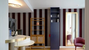 Um interior moderno com uma mesa de recepção, uma estante de madeira, um armário azul escuro e uma cadeira vermelha.