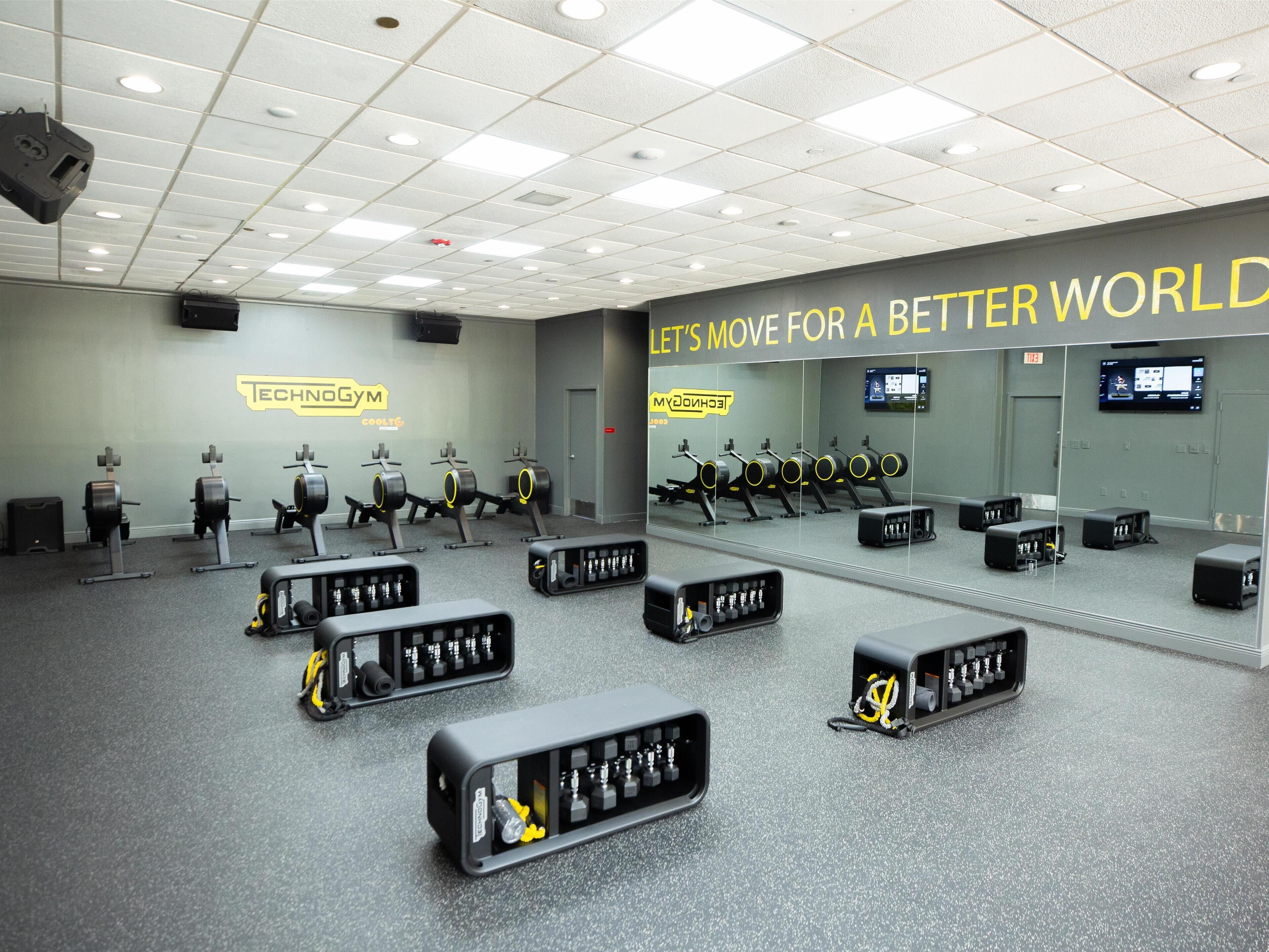 Uma academia com equipamentos de ginástica, espelhos e frases motivacionais na parede.