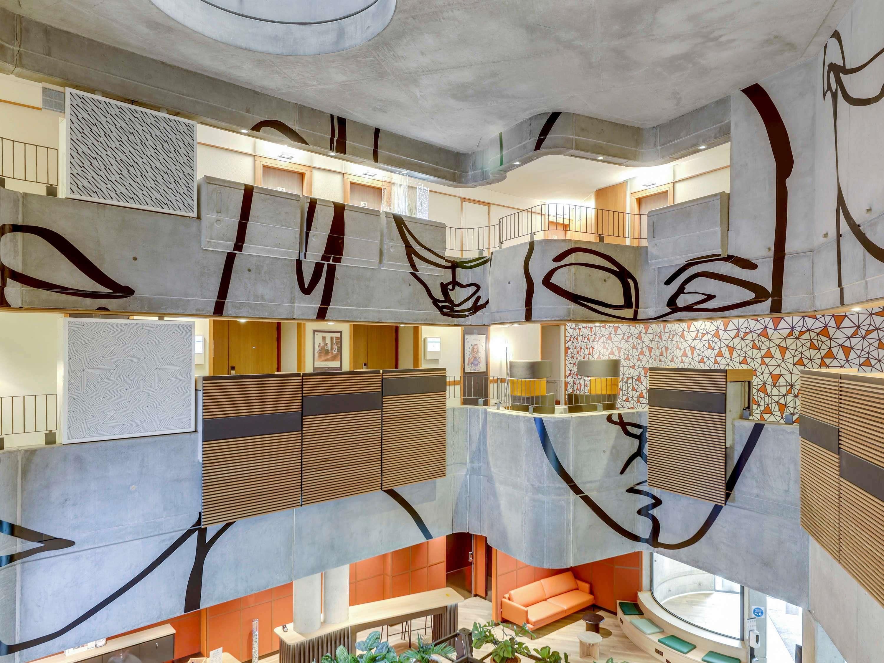 Um interior com vários níveis e design moderno, apresentando uma área de estar central, uma escadaria e uma parede com padrão.