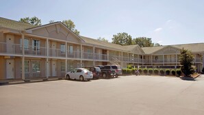 Um motel com vários andares, área de estacionamento coberta e um pátio central.
