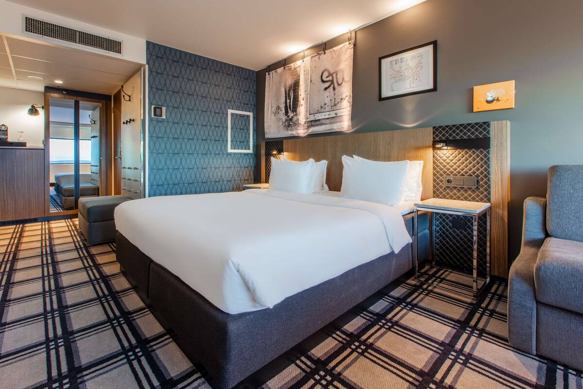 Quarto de hotel moderno com uma cama grande, uma escrivaninha e um espaço de estar.
