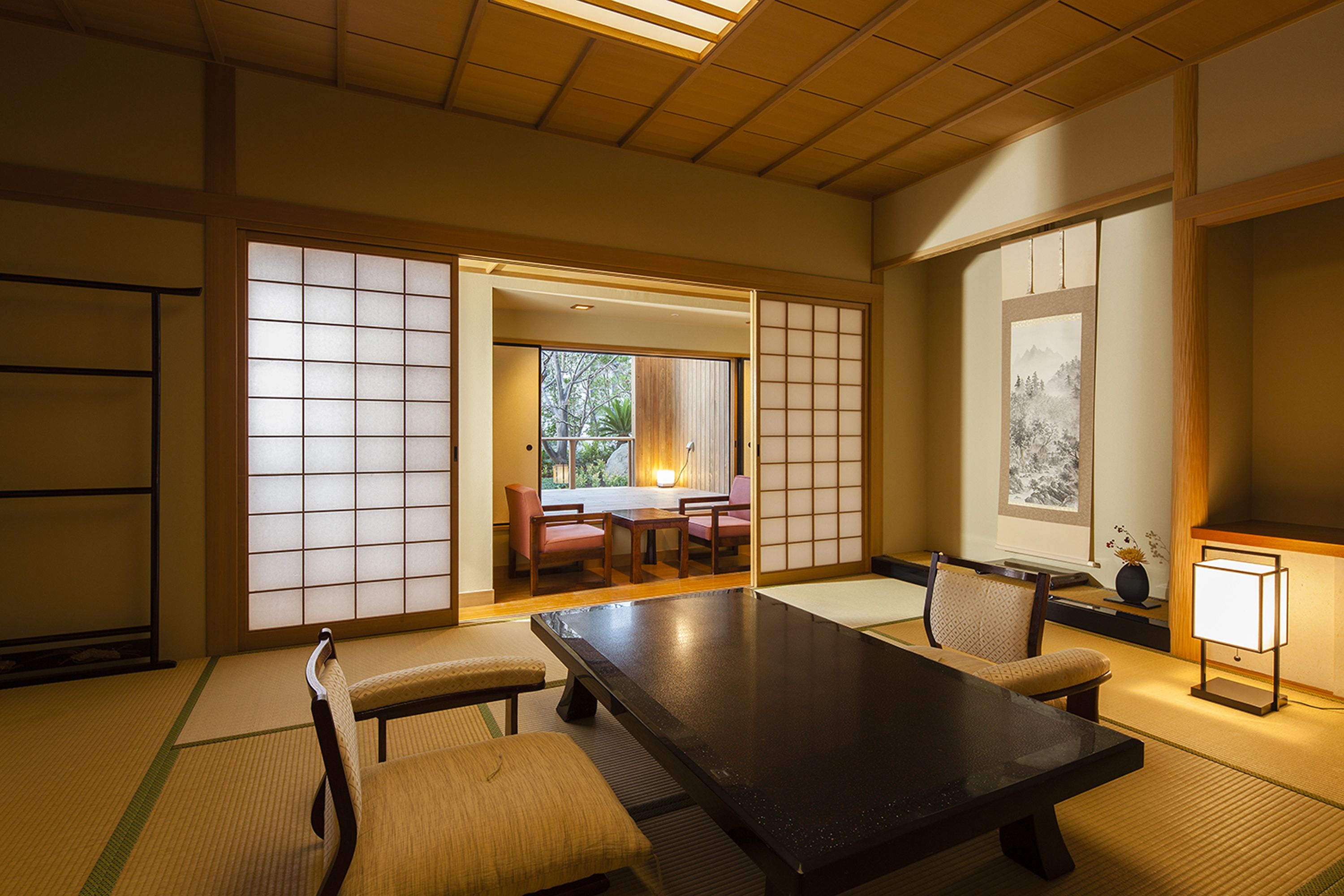 Um quarto japonês tradicional com tatames, uma mesa baixa e portas deslizantes.
