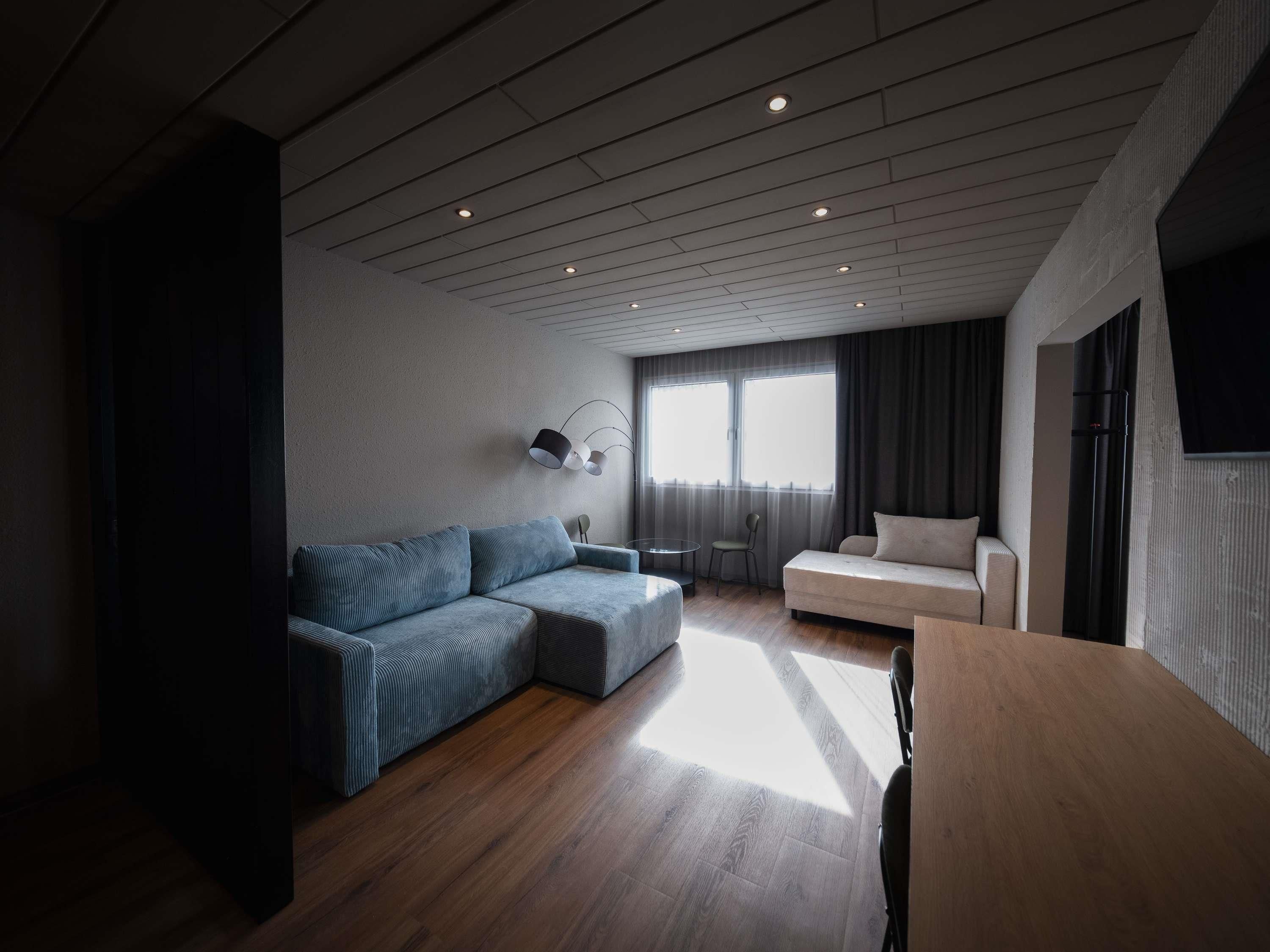Uma sala de estar moderna com um sofá seccional, uma mesa pequena e uma televisão.