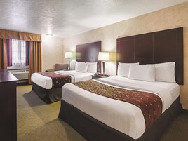 Quarto de hotel com duas camas, uma mesa e uma cadeira.