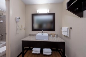Casa de banho com lavatório, espelho, porta-toalhas e secador de cabelo na parede.