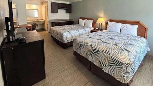 Quarto de hotel com duas camas, uma escrivaninha e uma televisão.