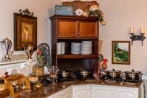 Uma cozinha com armário de madeira, bancada de mármore e diversos utensílios.