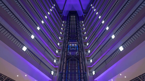 Interior com vários níveis, um eixo de elevador central e um design arquitetônico moderno.