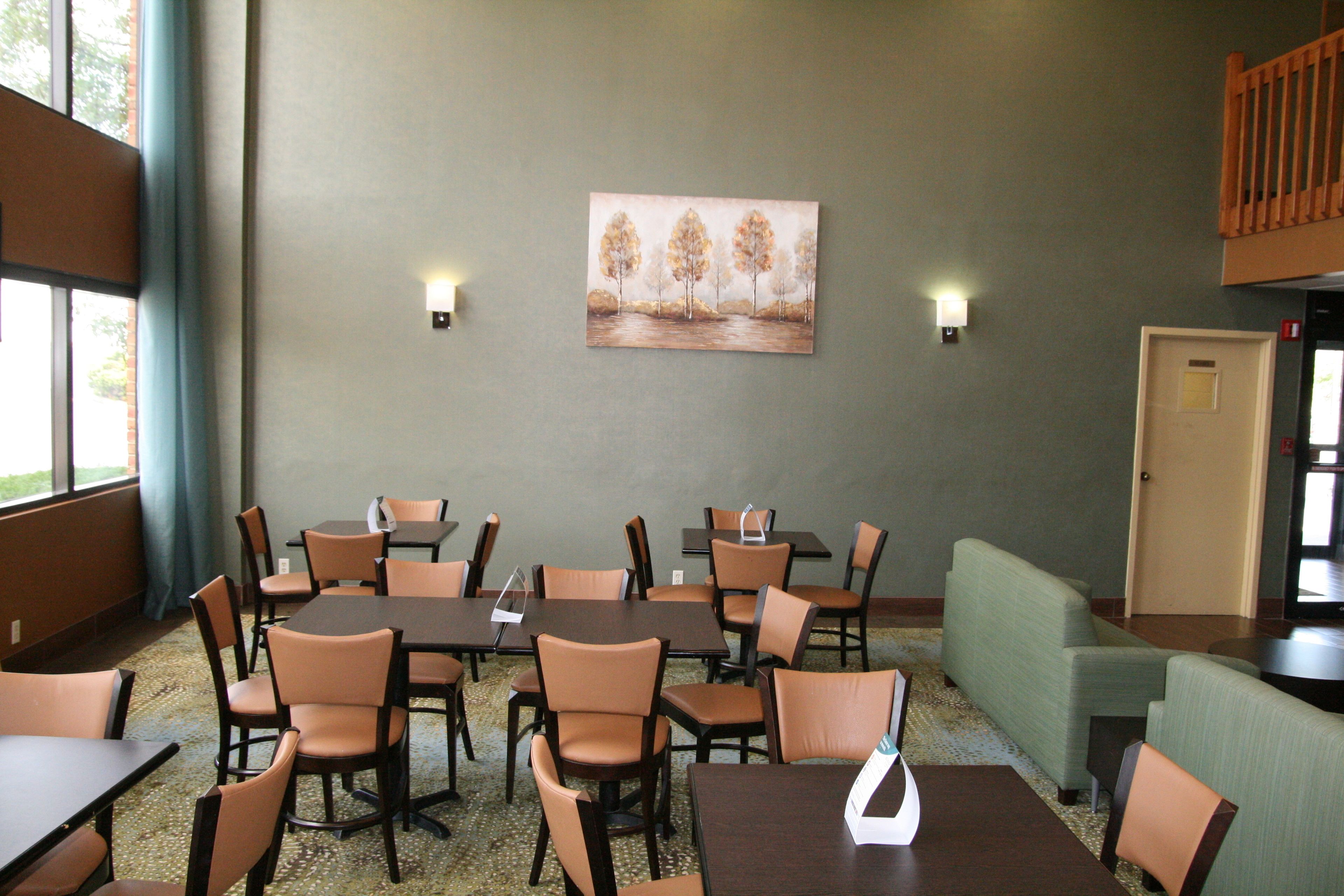 Uma sala de conferências com mesas e cadeiras, um quadro na parede e uma porta.