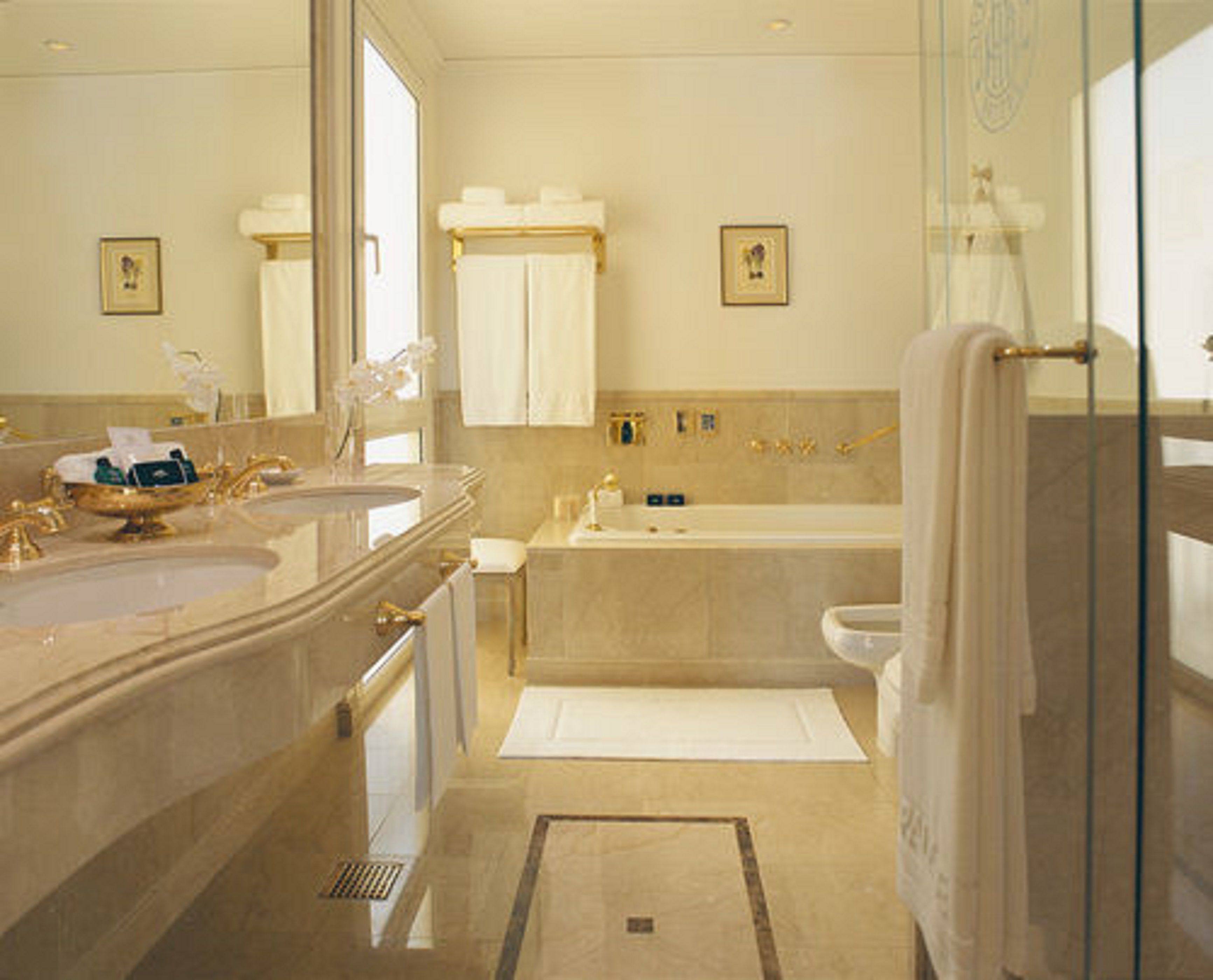 Um banheiro luxuoso com uma grande pia de mármore, uma banheira e um box de vidro.
