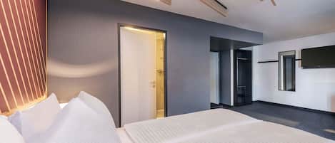 Quarto de hotel moderno com uma cama grande, closet espaçoso e área de chuveiro.