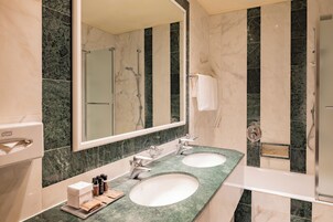 Uma casa de banho moderna com duas pias, um espelho grande e um chuveiro.