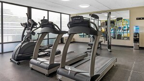 Uma academia com esteiras, equipamentos de ginástica e um bebedouro.