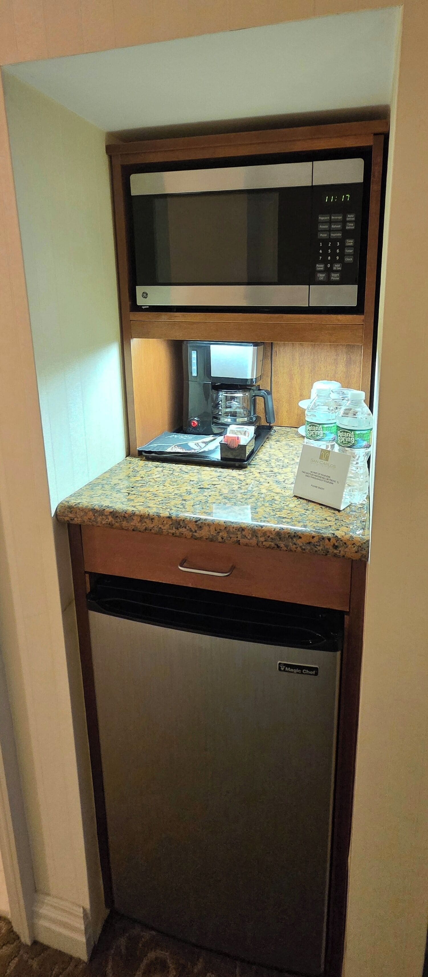 Cozinha compacta equipada com micro-ondas, máquina de café e lava-louças.
