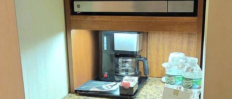 Cozinha compacta equipada com micro-ondas, máquina de café e lava-louças.