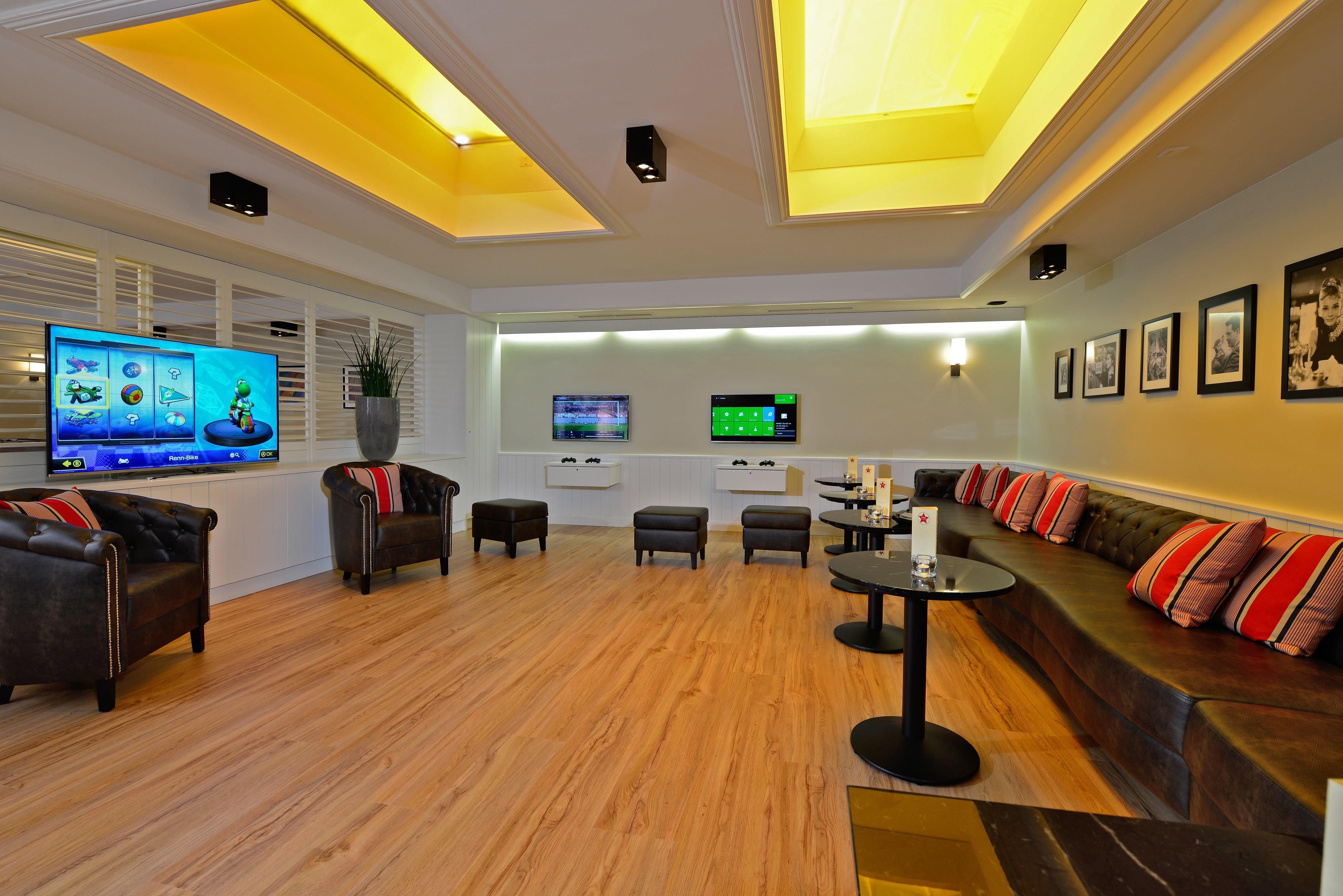 Uma sala de estar moderna com televisão de tela plana, assentos confortáveis e piso de madeira.