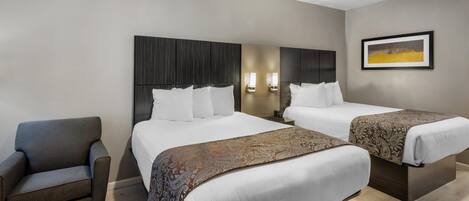 Quarto de hotel com duas camas, uma cadeira e um quadro na parede.
