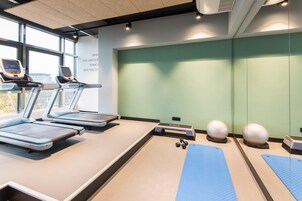 Uma academia com esteiras, bolas de exercício e uma parede com frases motivacionais.