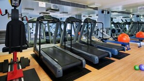 Uma academia com esteiras, máquinas de peso e bolas de exercício.