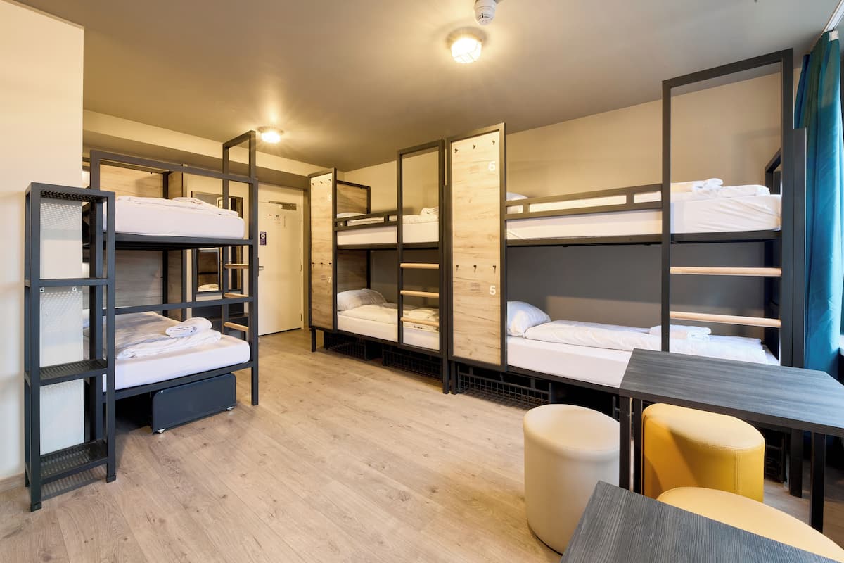 Um quarto tipo dormitório com beliches, escrivaninha e cadeira.