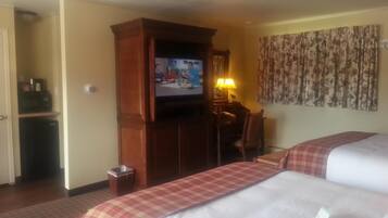 Quarto de hotel com duas camas, televisão, escrivaninha e uma cadeira, e um abajur.