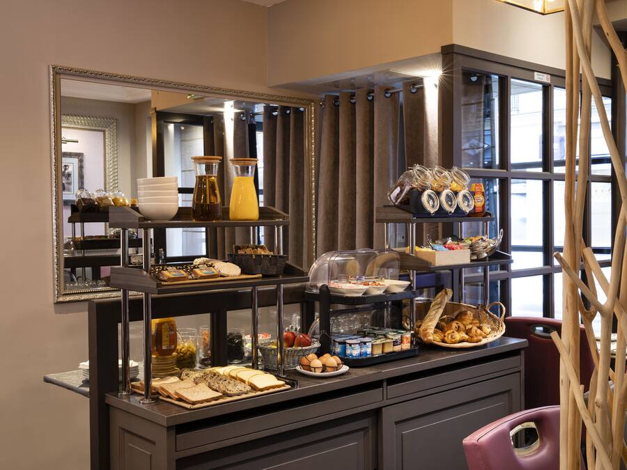 Uma mesa de buffet com diversos alimentos e bebidas, um espelho e uma janela com cortinas.