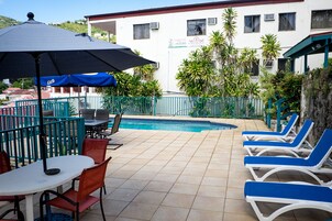 Uma área na piscina com espreguiçadeiras, uma mesa e um guarda-sol.