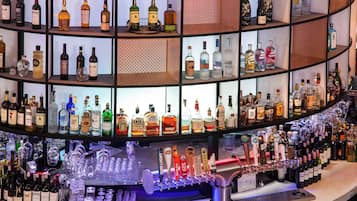 Um bar com várias prateleiras cheias de garrafas de bebidas e um balcão com várias torneiras.